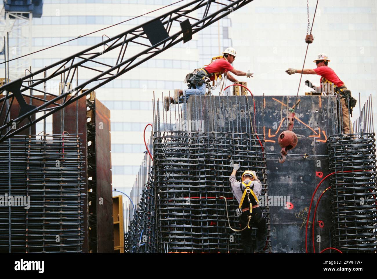 Workers collaborate to lift materials while constructing a large ...