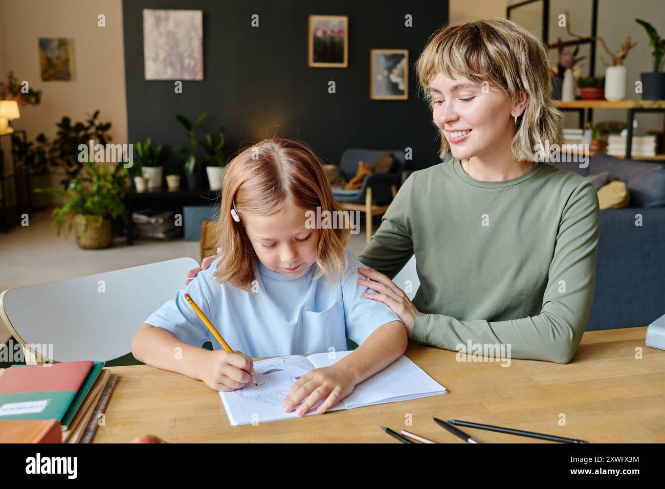 Blonde mom supporting her daughter while she writing essay for school ...