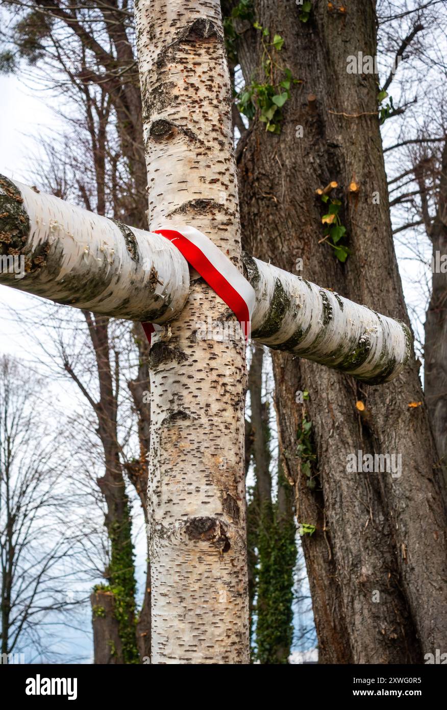 A birch cemetery cross with an emblem in Polish national colors. A ...