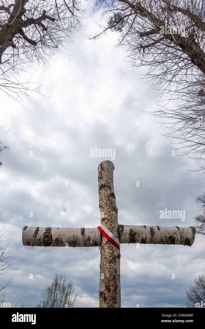 A birch cemetery cross with an emblem in Polish national colors. A ...
