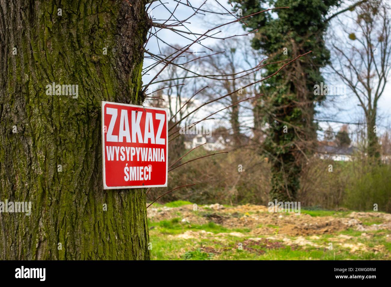 A red warning sign on a tree with the text "No dumping garbage". Social ...