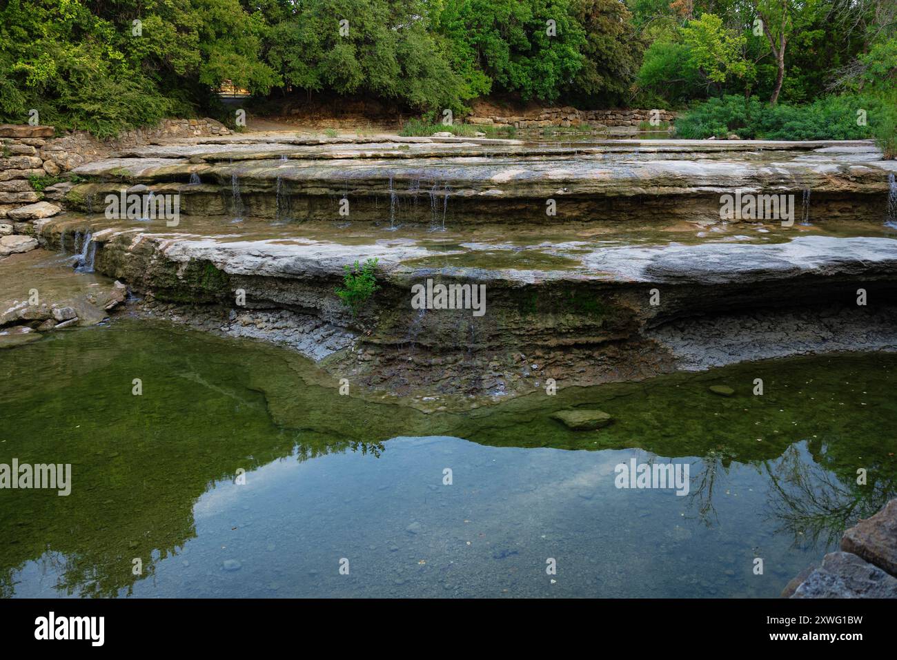 A serene natural rock formation with cascading water in a lush green ...