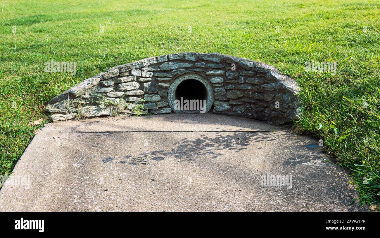 Drainage culvert surrounded by grass and funneling to paved trench to ...