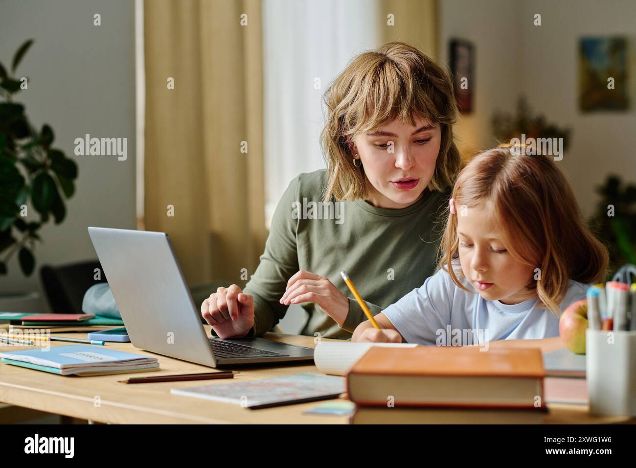 Young mom checking daughters homework while working remotely, little ...