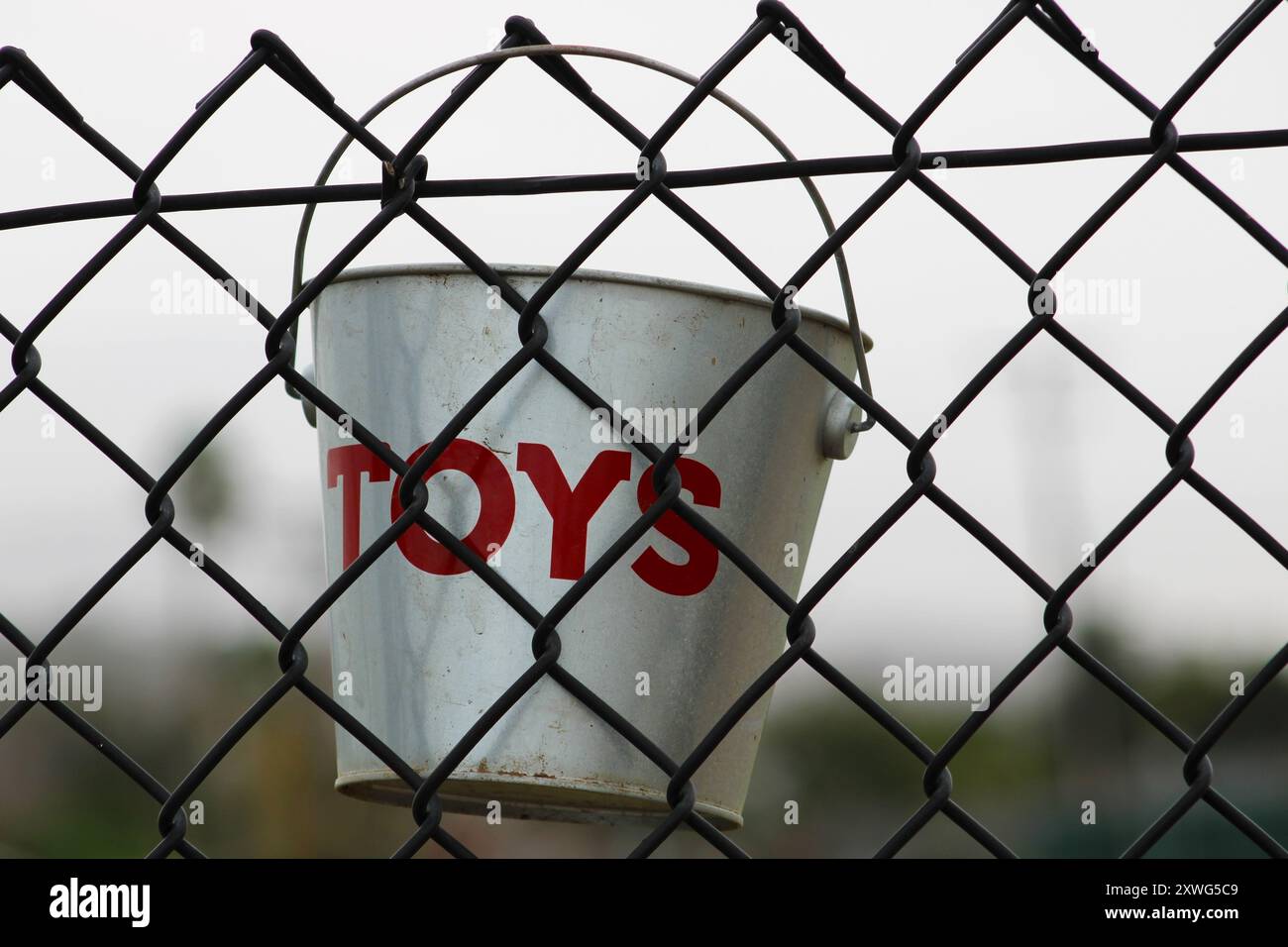 silver toy bucket with red lettering hanging from fence Stock Photo - Alamy