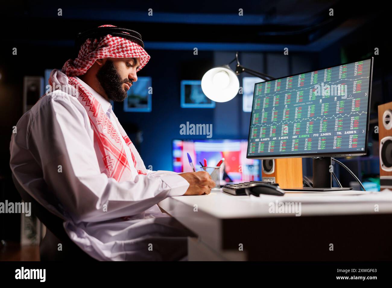 Engrossed in his work, Islamic man researches, write notes, and browses ...