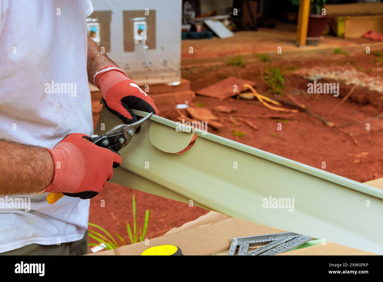 Before installing plastic vinyl siding, worker uses of scissors to cut ...