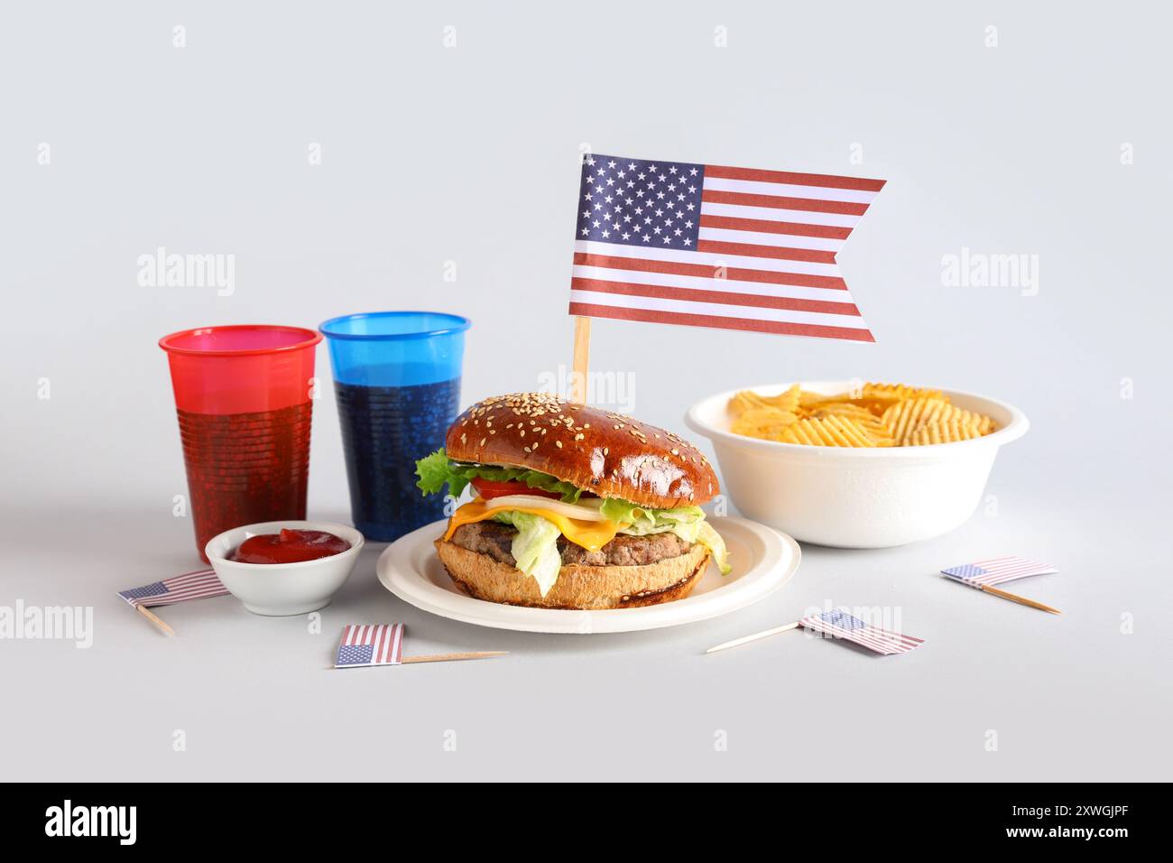 Tasty burger with flags of USA, cola and potato chips on white ...