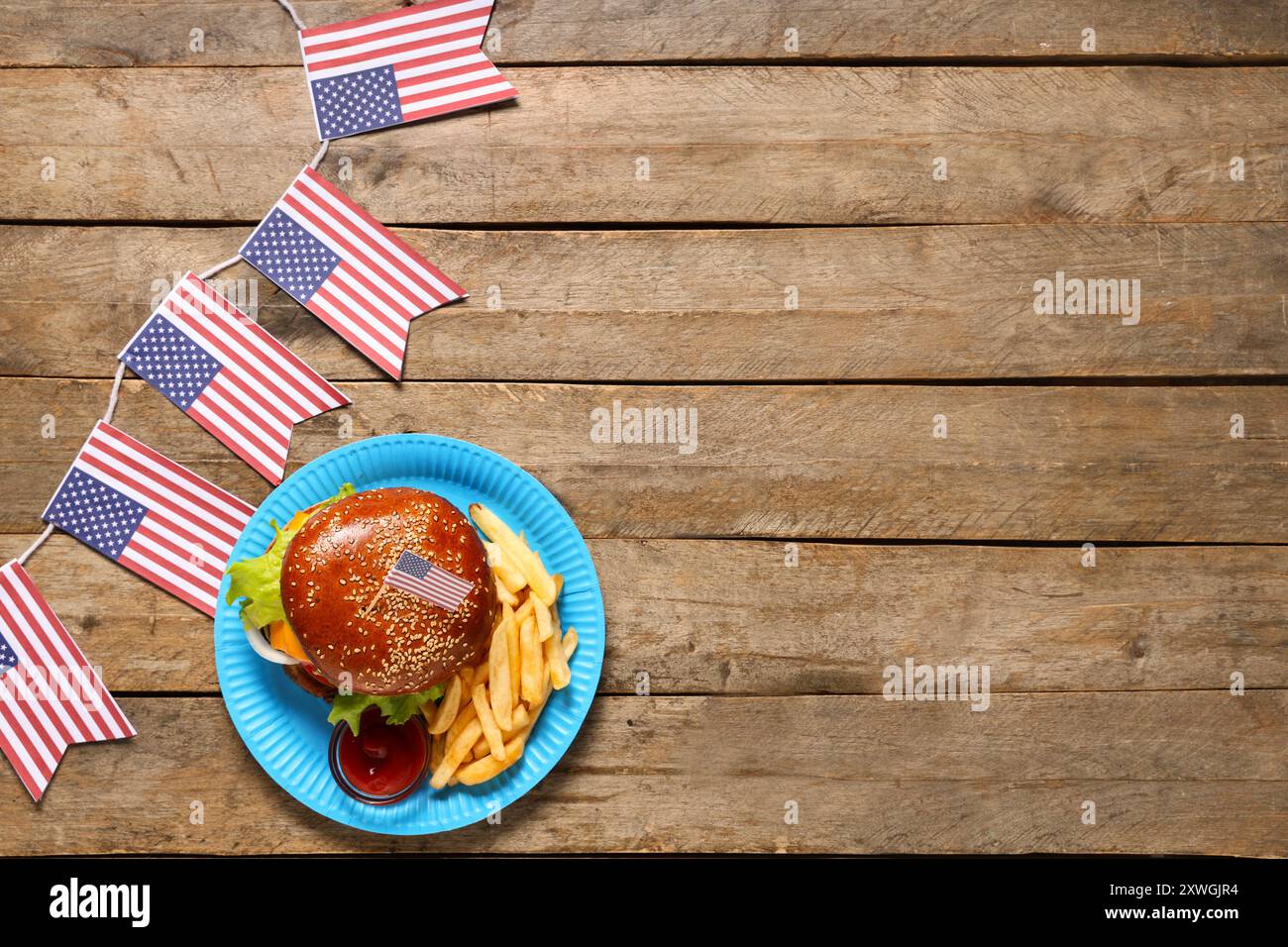 Tasty burger with french fries and flags of USA on wooden background ...