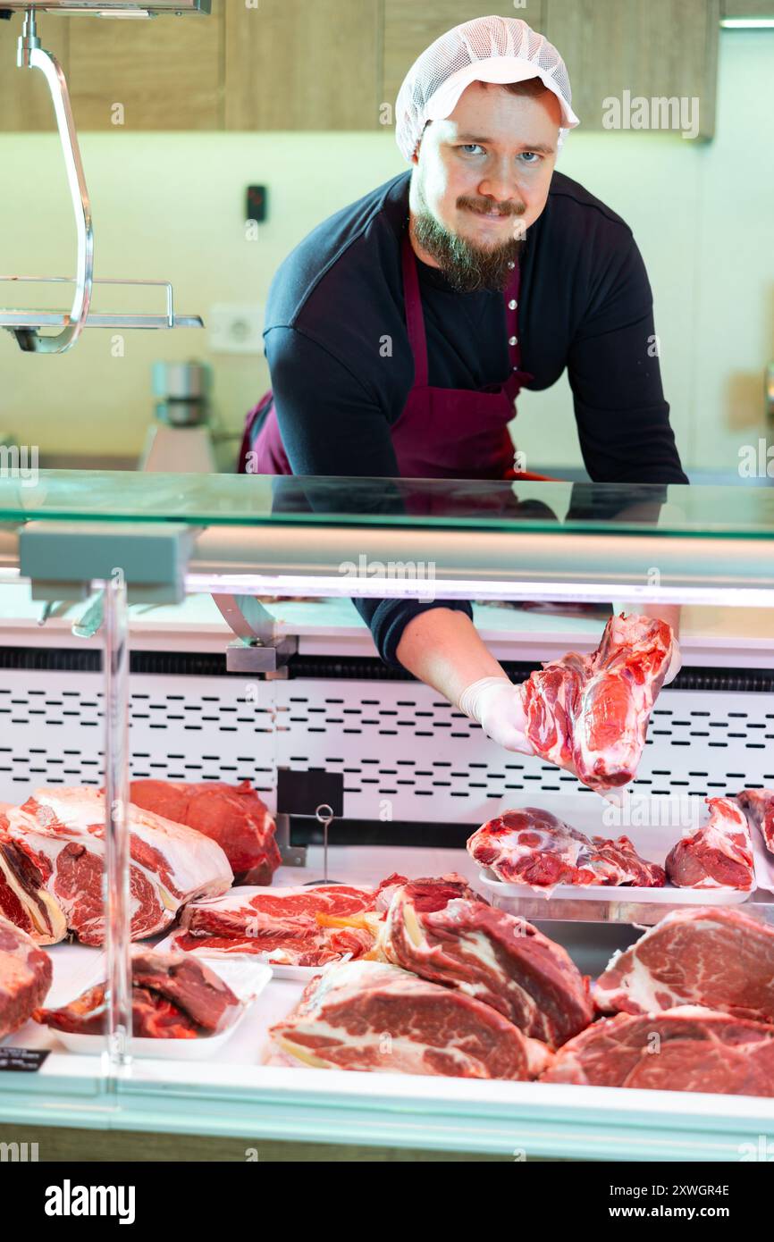 Male butcher putting raw meat on supermarket display Stock Photo - Alamy