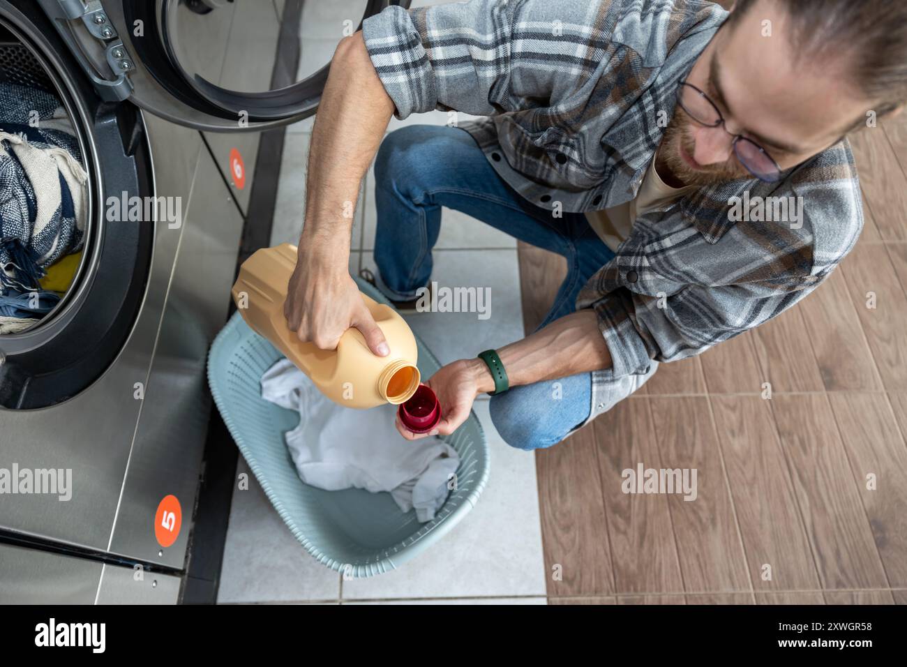 Bearded man washing clothes at commercial laundry facility Stock Photo ...