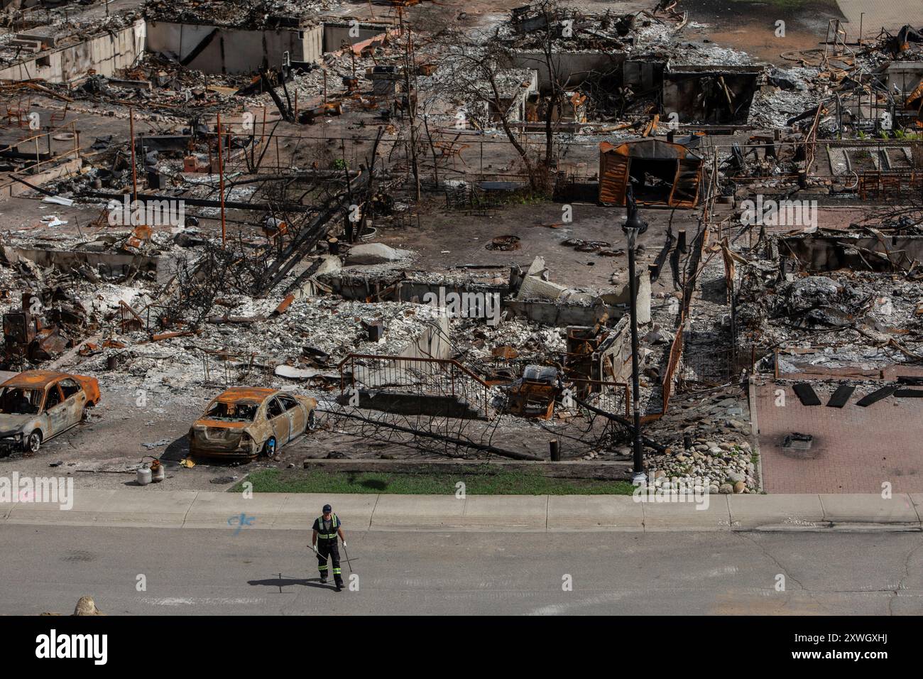 A worker walks in a devastated neighborhood in west Jasper, Alberta ...
