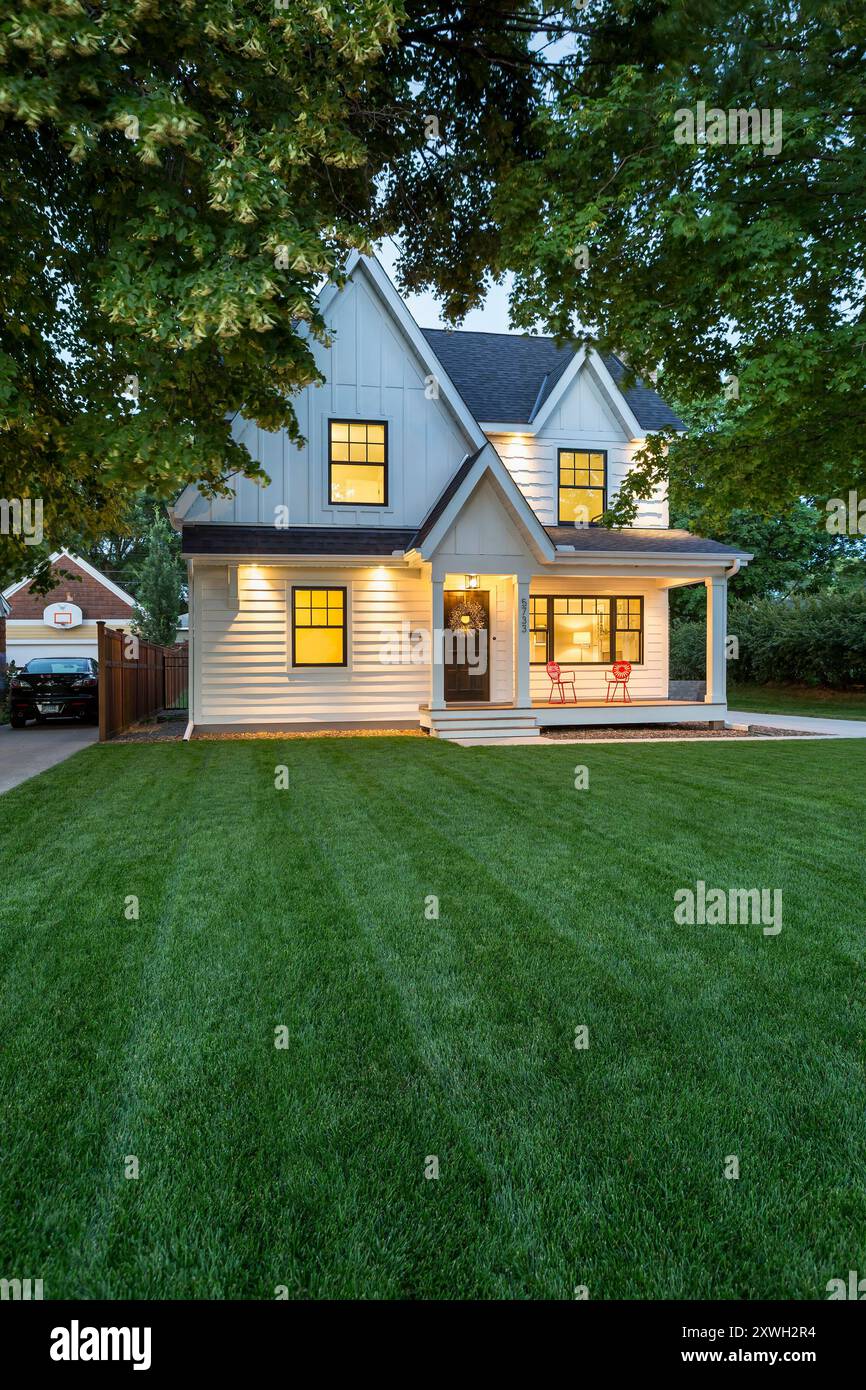 Front view of new white farmhouse style house surrounded by greenery ...