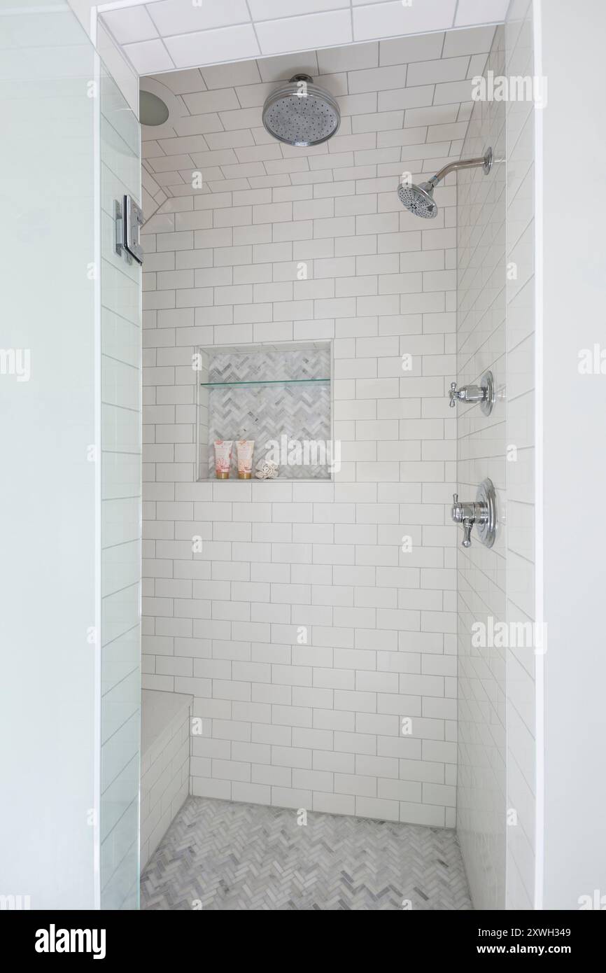 Interior of white tiled shower with built-in bench and two shower heads ...