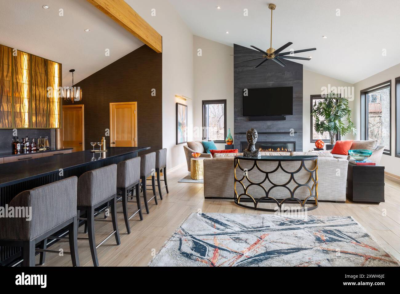 Bar area and living room with gray stone fireplace and cabinets with ...