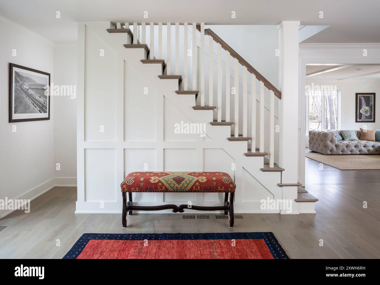 Stairway encased with wall panels and molding descends down into living ...