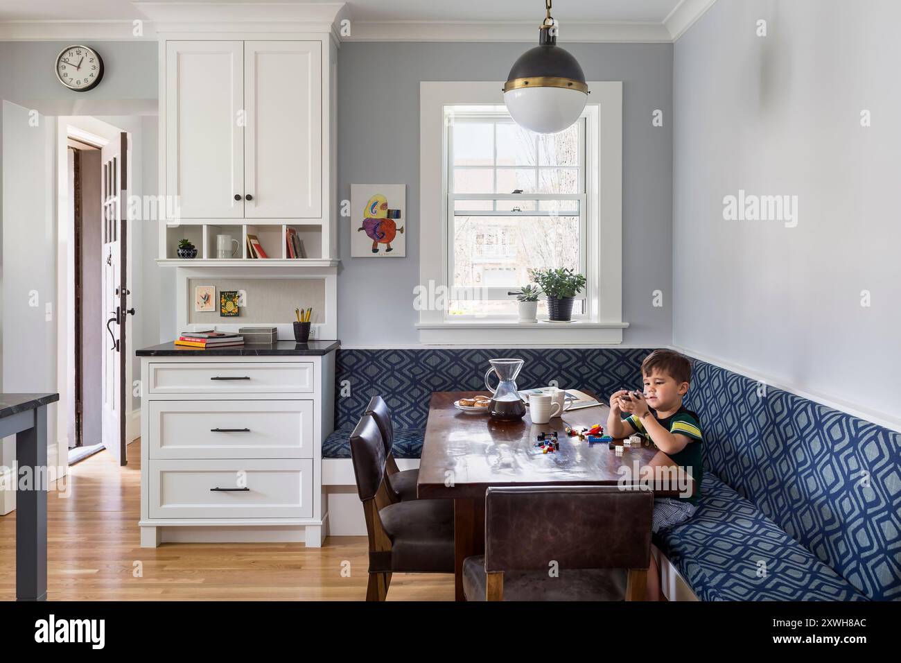 Table and banquette in corner of kitchen with small boy at table Stock ...