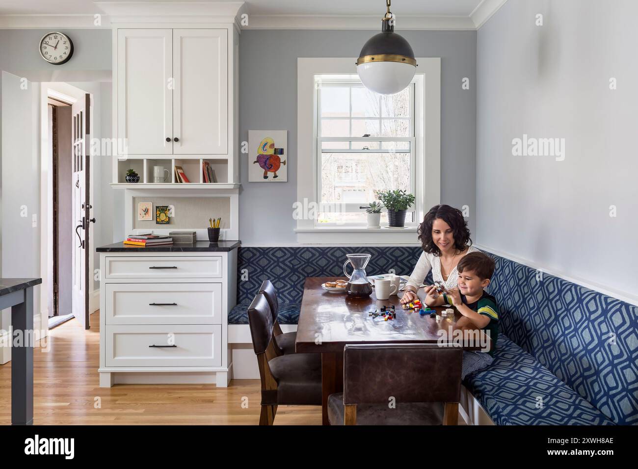 Table and banquette in corner of kitchen with mother and son sitting at ...