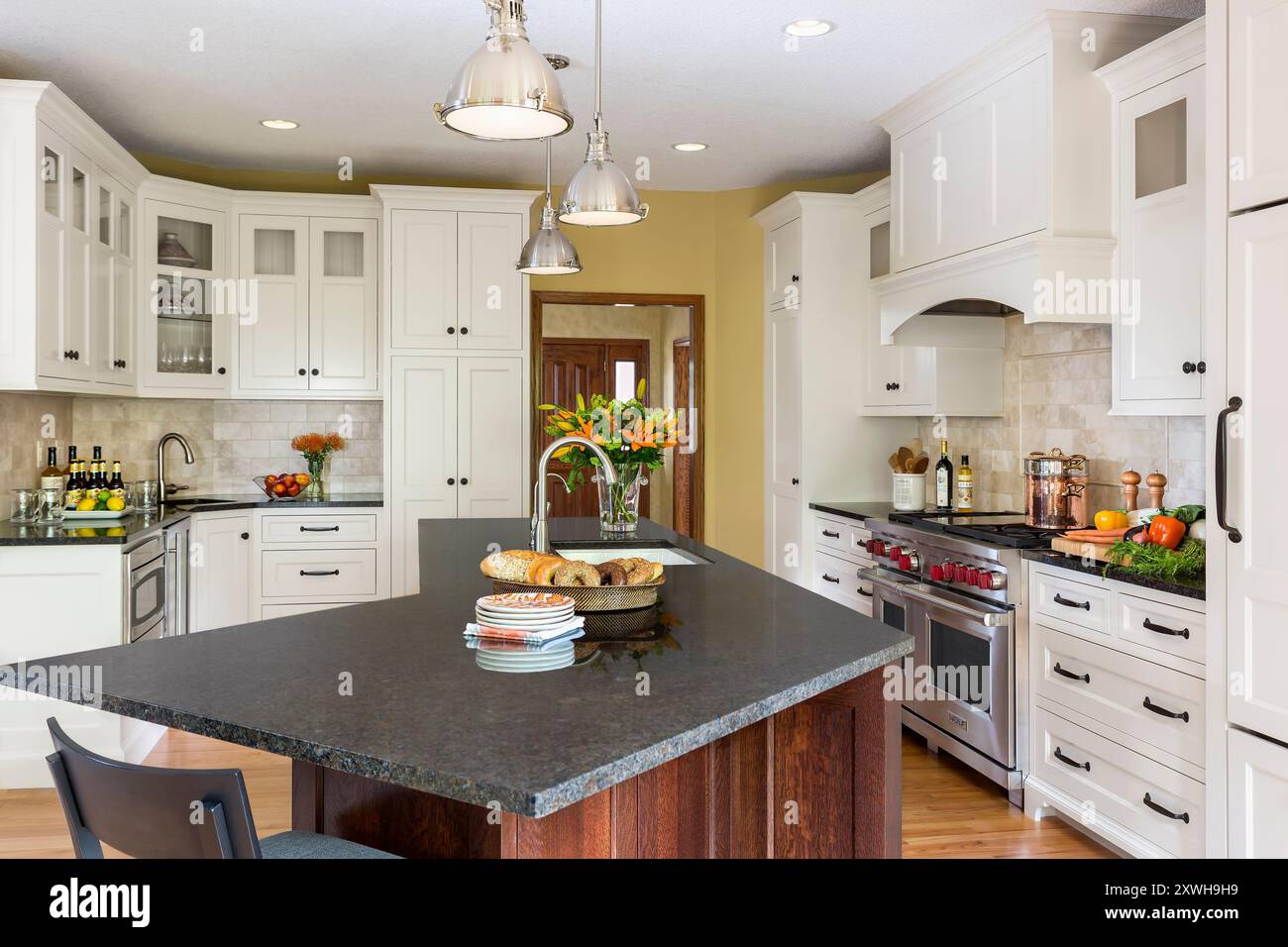 Large kitchen with cream colored cabinets, large dark wood island and ...