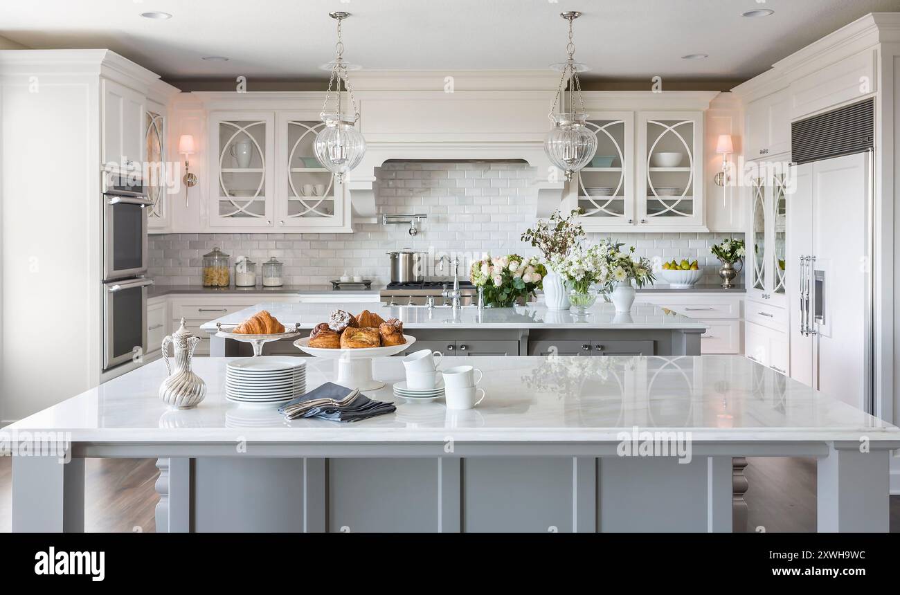 High end white kitchen with two islands and lots of beautiful flowers ...