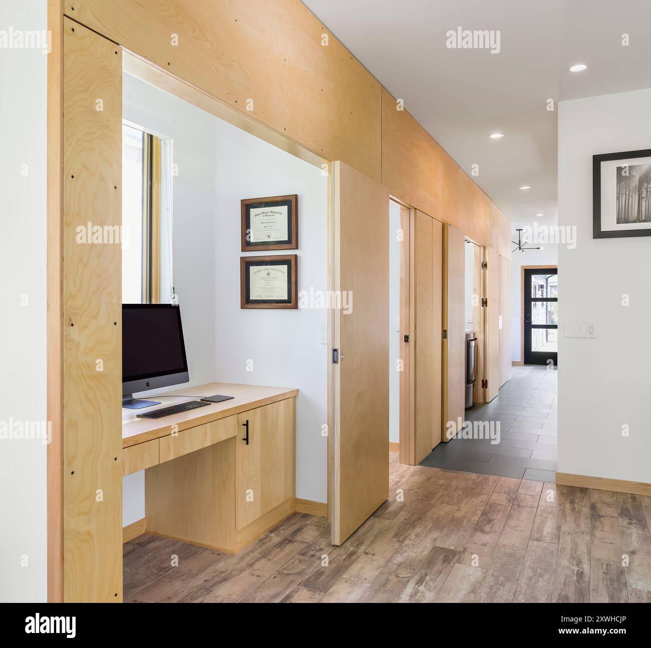Long hallway entry into home with built-in birch doors hiding storage ...