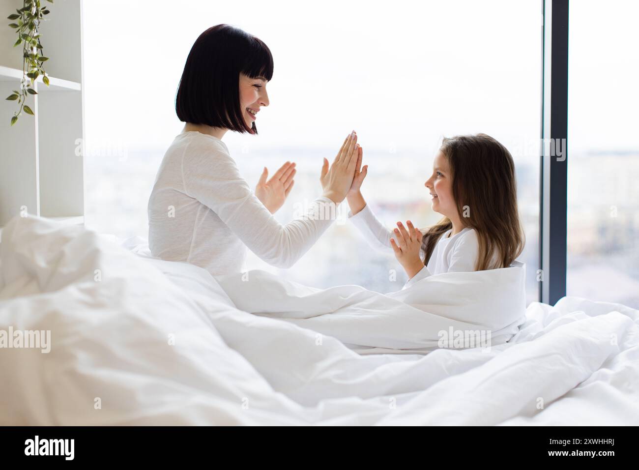 Mother and daughter playing clapping game in bed Stock Photo - Alamy