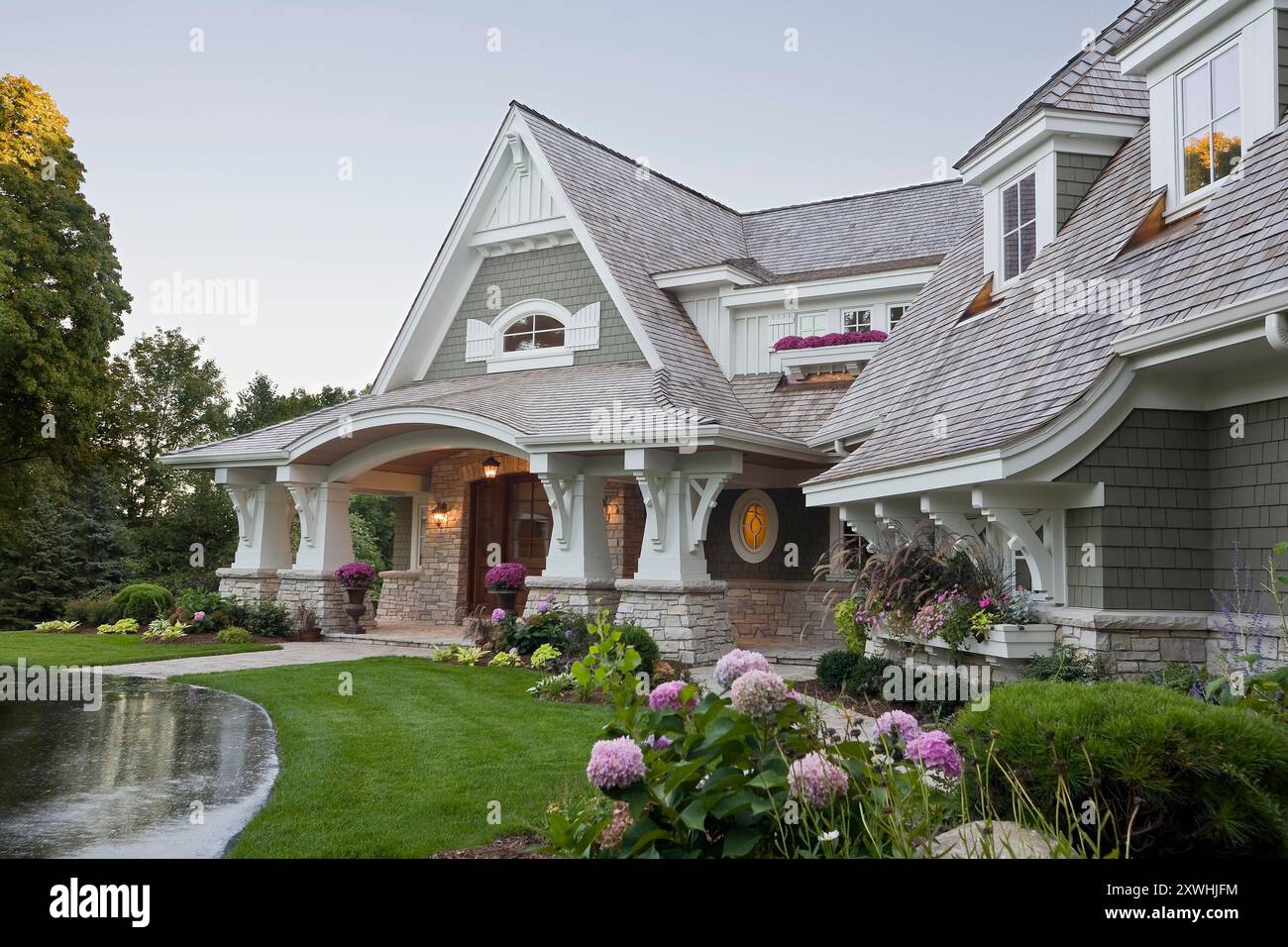 Closer view of large cottage style house with green grass and flowers ...
