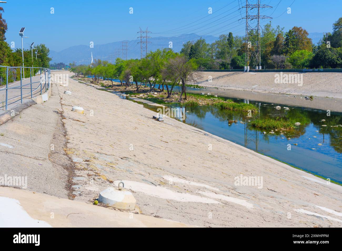 Wide pedestrian and bike path beside Los Angeles River with greenery in ...