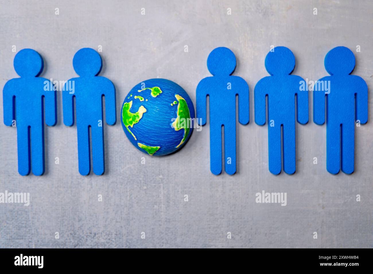 A miniature globe between a row of blue human figures ...