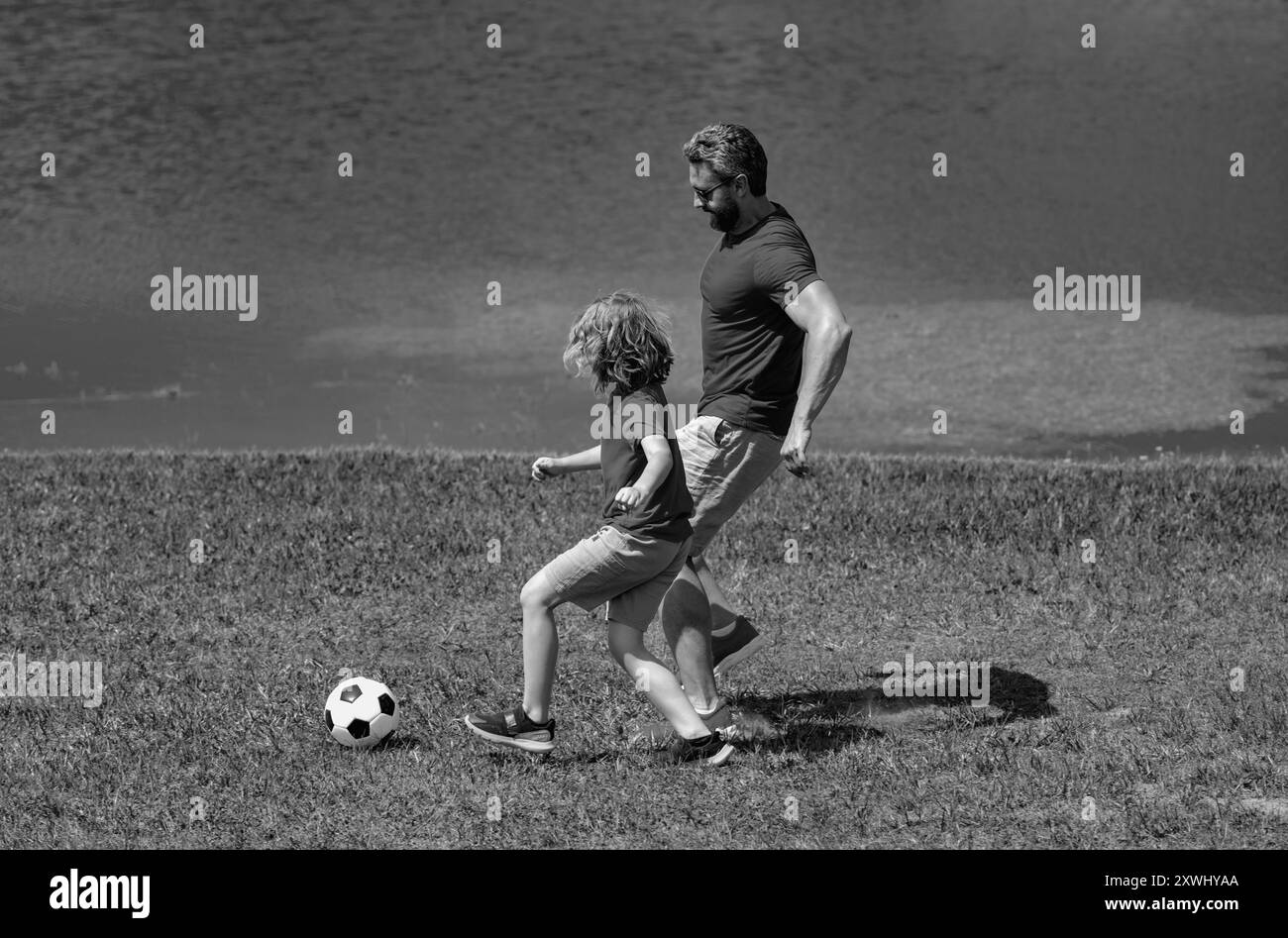 Dad and son playing football together on green meadow. Father and son ...
