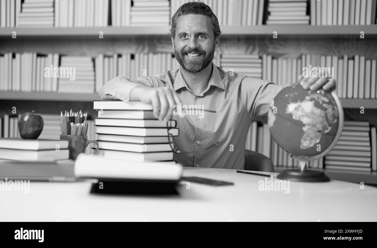 Portrait of school teacher with book in classroom. Handsome teacher in ...
