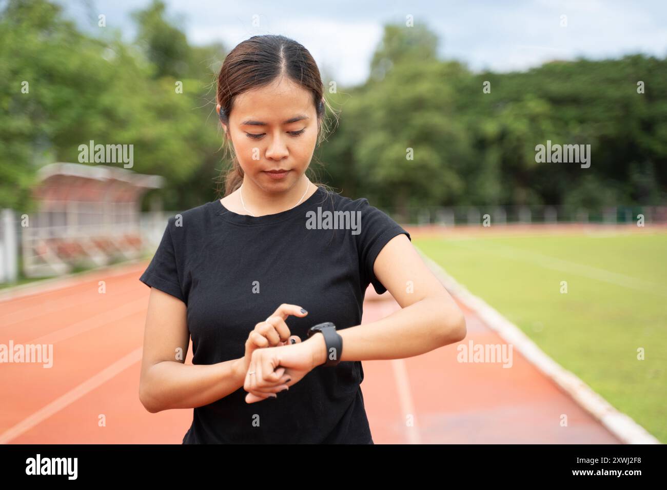 Young Asian female runner checing her run time on her smart watch after ...