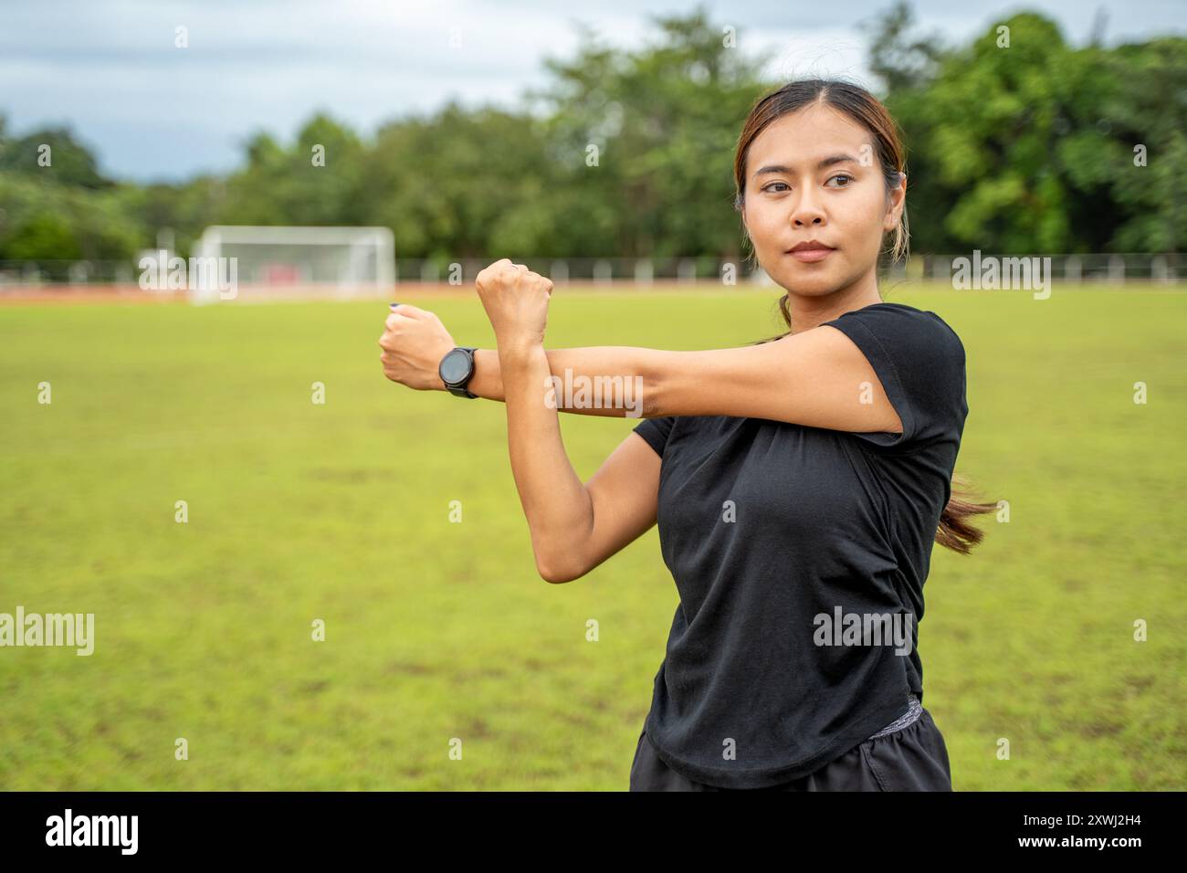 Young female runner stretching her arm during her warm up before her ...