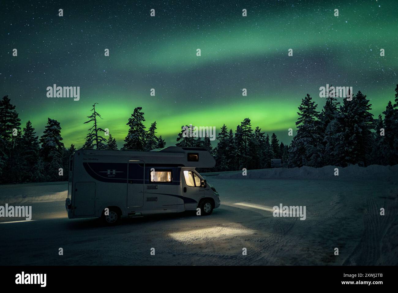 Northern lights over a motorhome and a snowy forest at night (Lapland ...