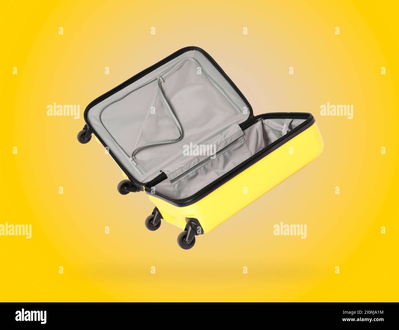 Open empty suitcase in air on yellow background Stock Photo - Alamy