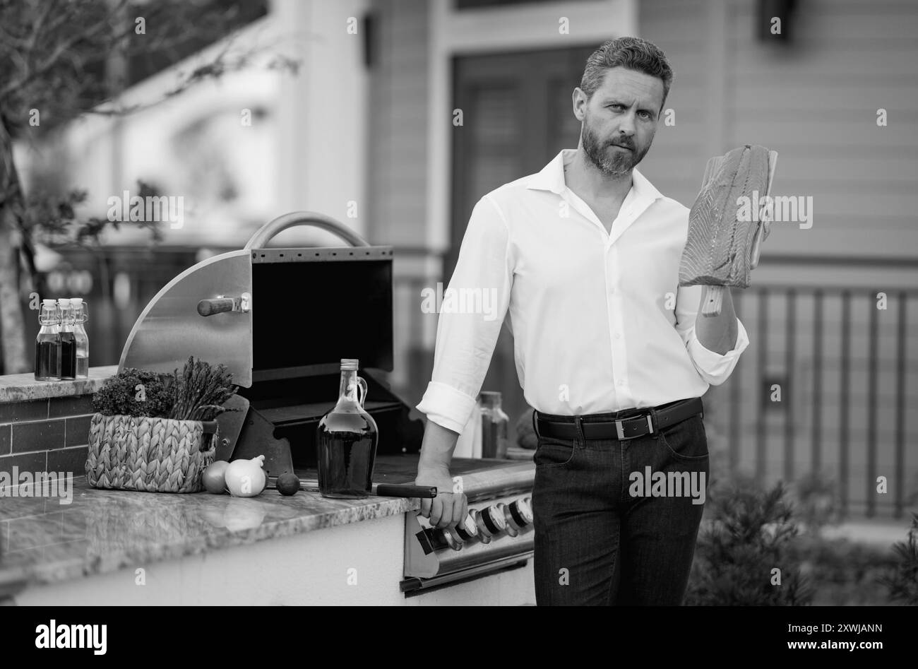 Handsome man preparing salmon fillet on barbecue. Male cook cooking ...