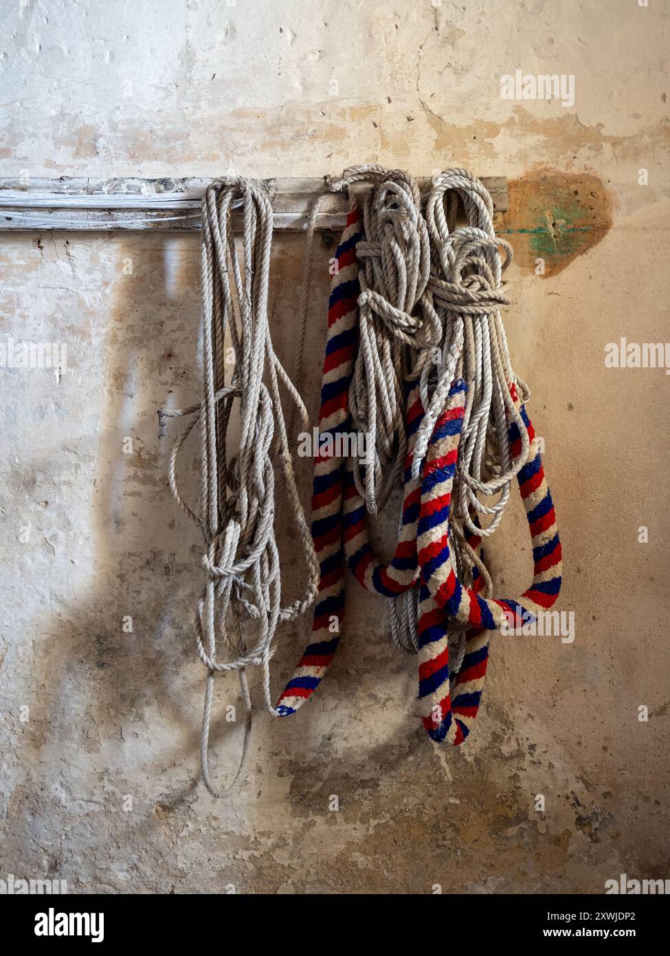 Old worn bell ropes, both plain and striped, hanging from hooks in the ...