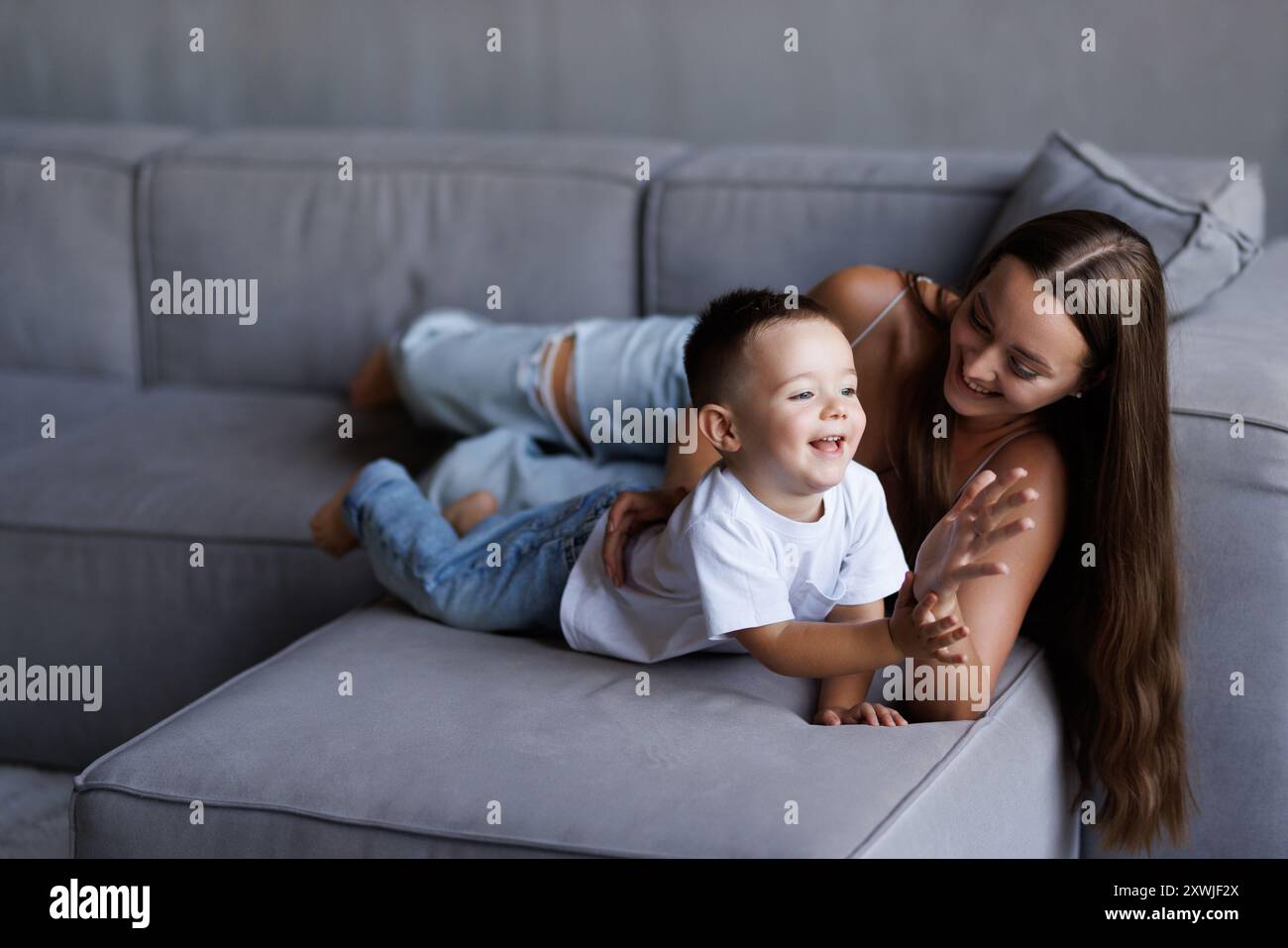 Happy little son hugging laughing mom, sitting on lap, speaking ...