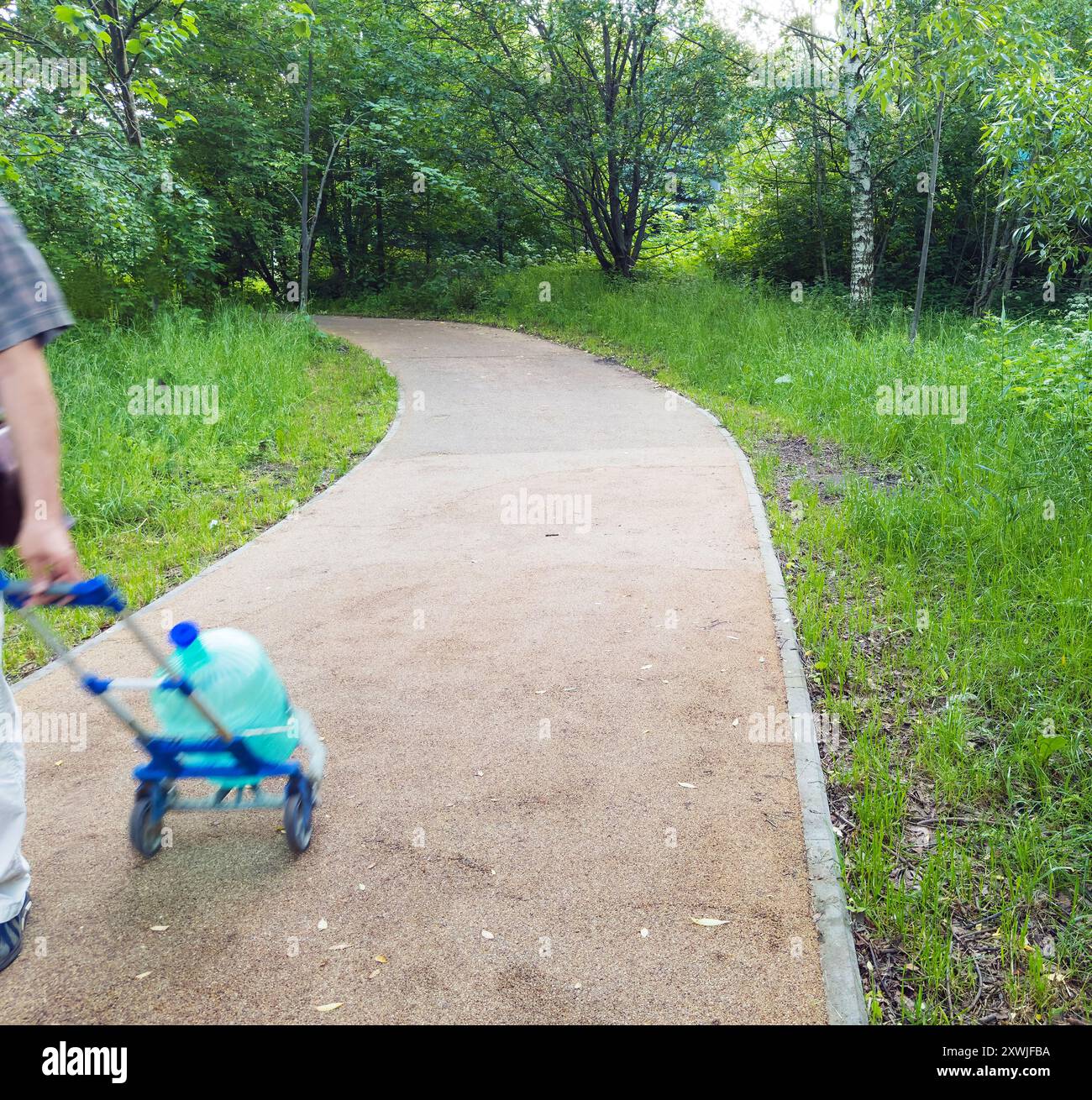 man carries a big bottle of spring water from the park on a hand cart ...