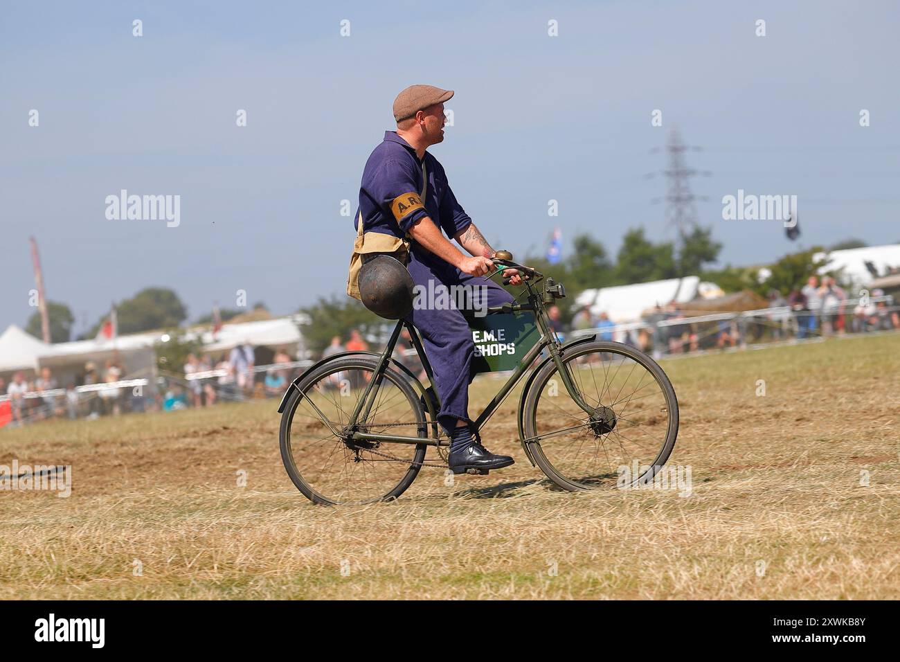 A reenactor on a bicycle joins the military vehicle parade at The ...