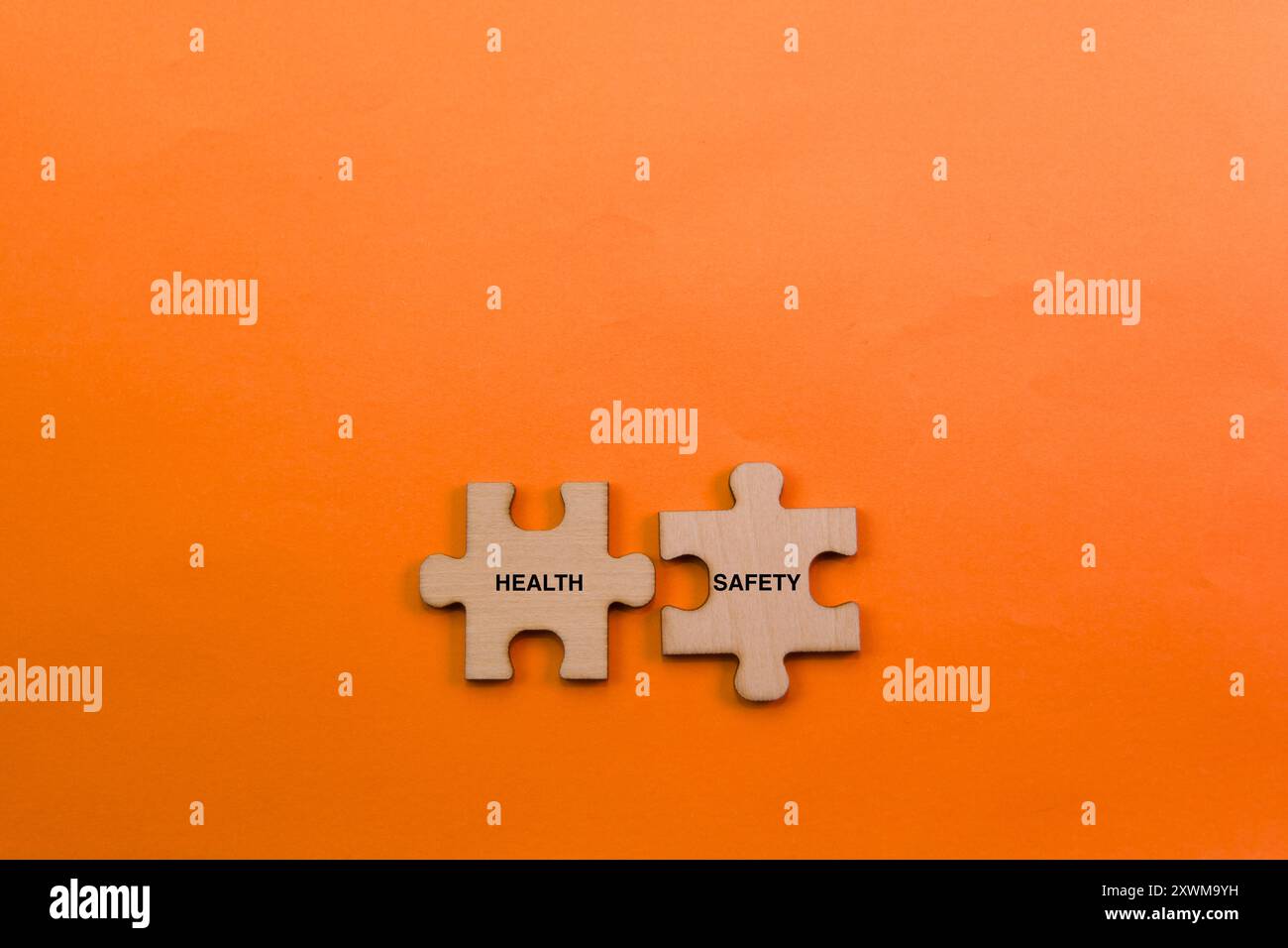 Two wooden puzzle pieces fit together on a vibrant orange background ... Two wooden puzzle pieces fit together on a vibrant orange background ...