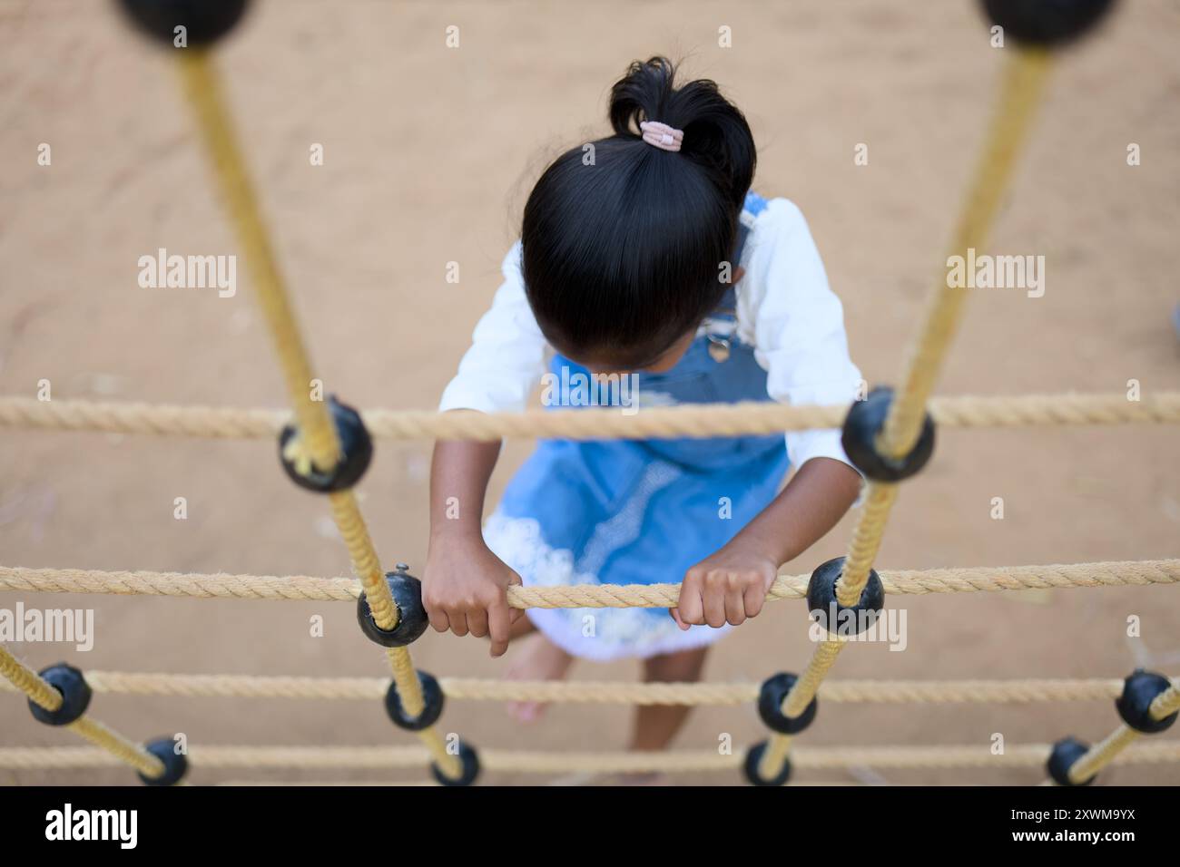 Determined young girl navigating a rope ladder, showcasing courage and ...