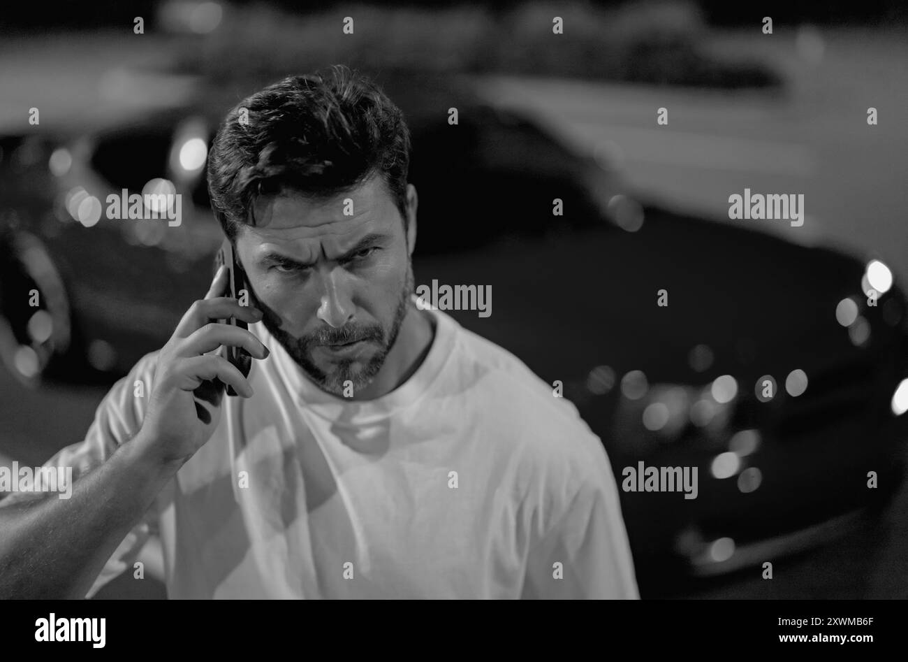 Gangster, criminal concept. Angry man near car on night urban street ...