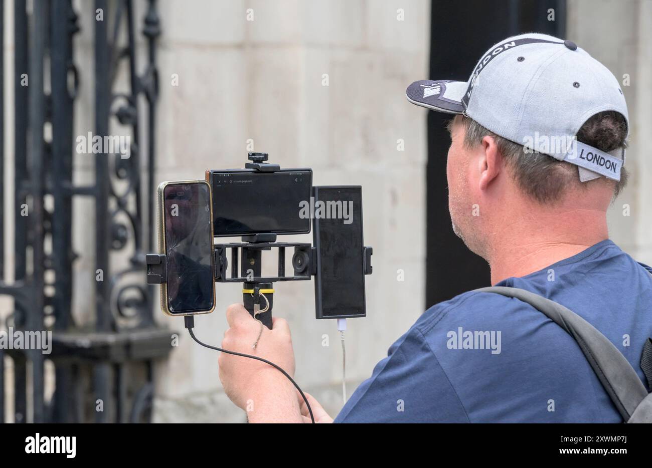 London, UK. Man filming with three mobile phones outside Horse Guards ...