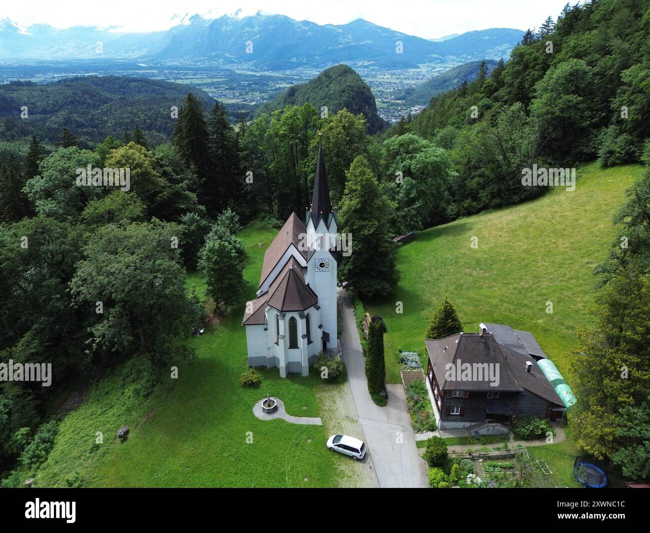 An aerial view of Kuratienkirche Meschach surrounded by lush greenery ...