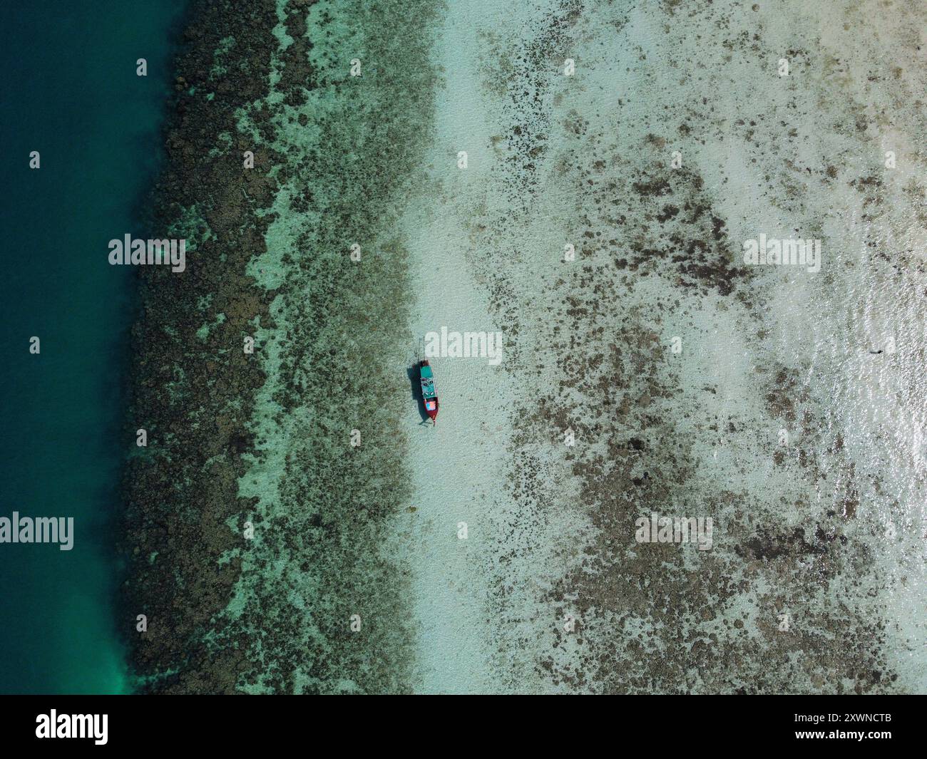 Aerial view of a long tail boat sailing next to an underwater cliff ...