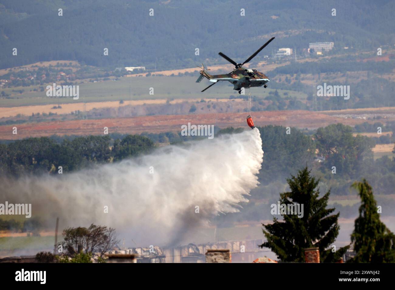 A military helicopter extinguishes fire on the ground with a helicopter ...