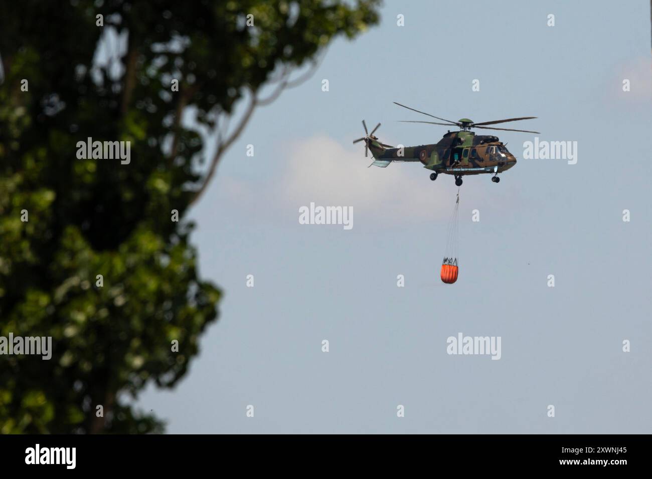 A military helicopter carries water with a helicopter bucket (helibucket Stock Photo - Alamy