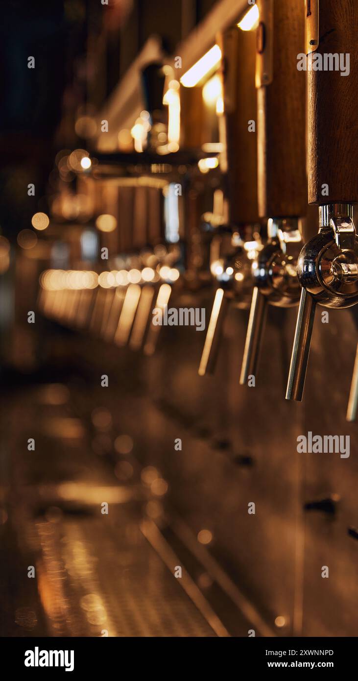 Row of golden shiny beer taps with wooden handles, set against dark ...