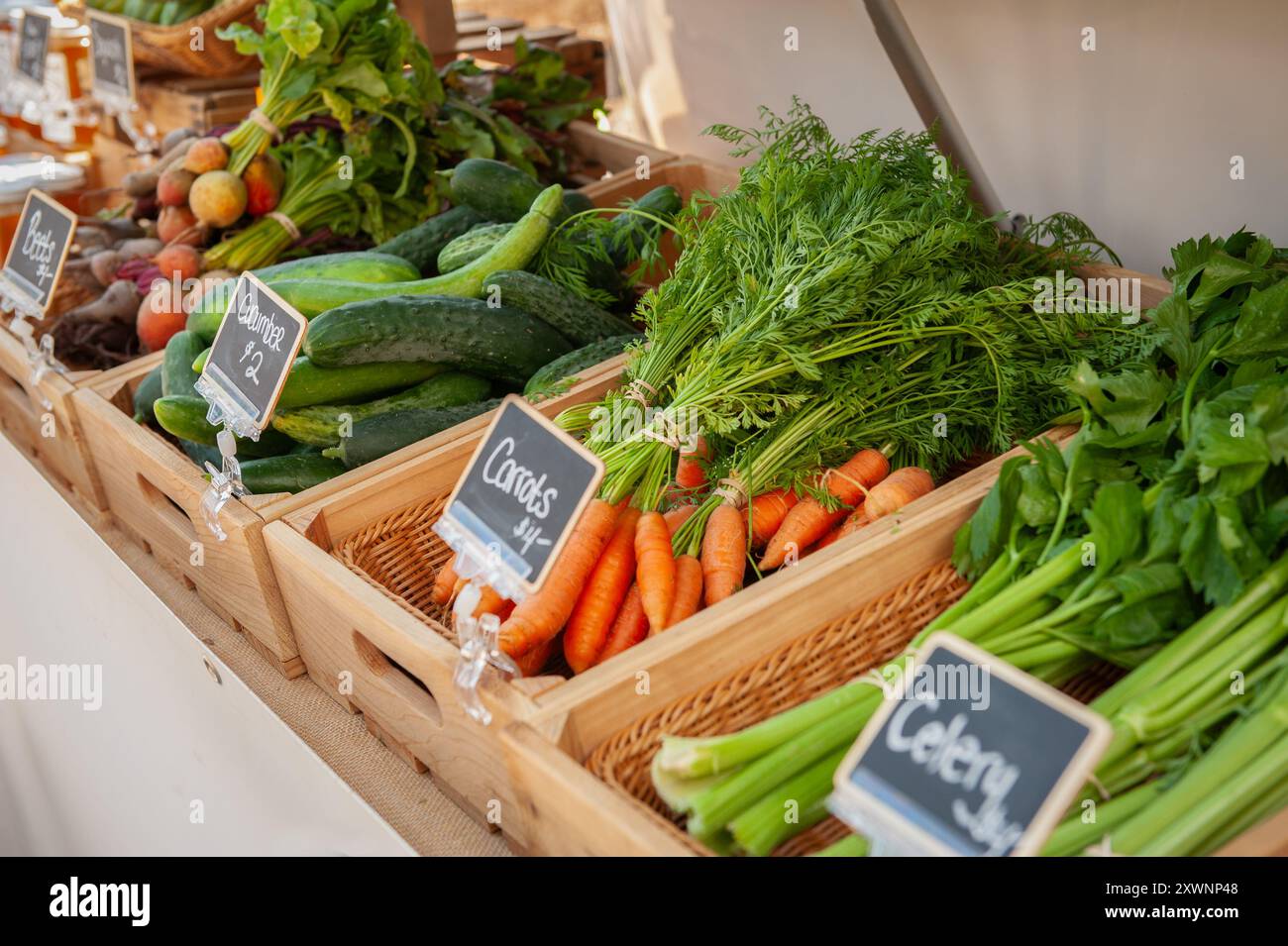 A variety of fresh vegetables displayed in wooden crates at a farmer's ...